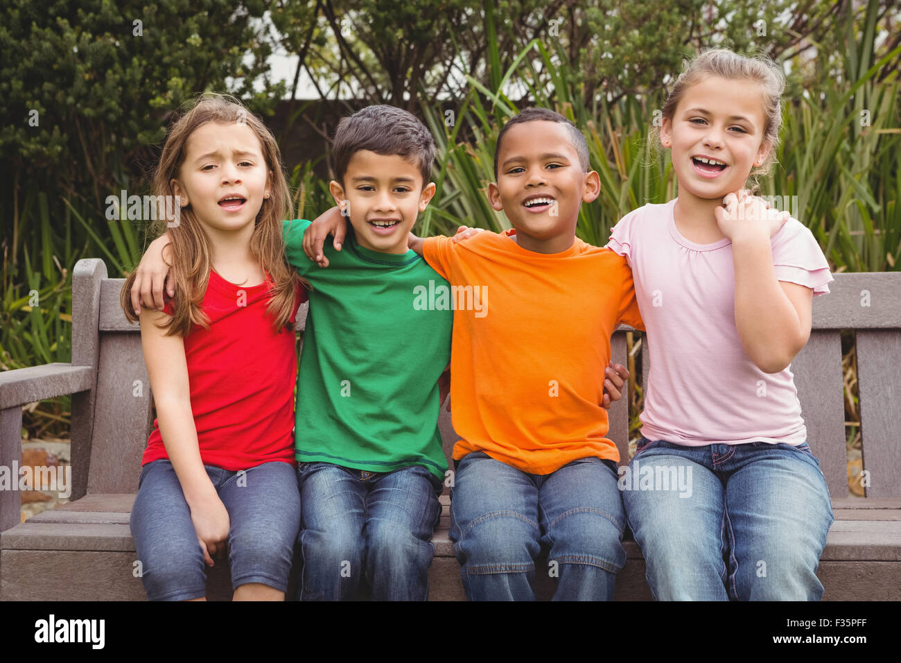 Happy children sitting together on a bench Stock Photo - Alamy
