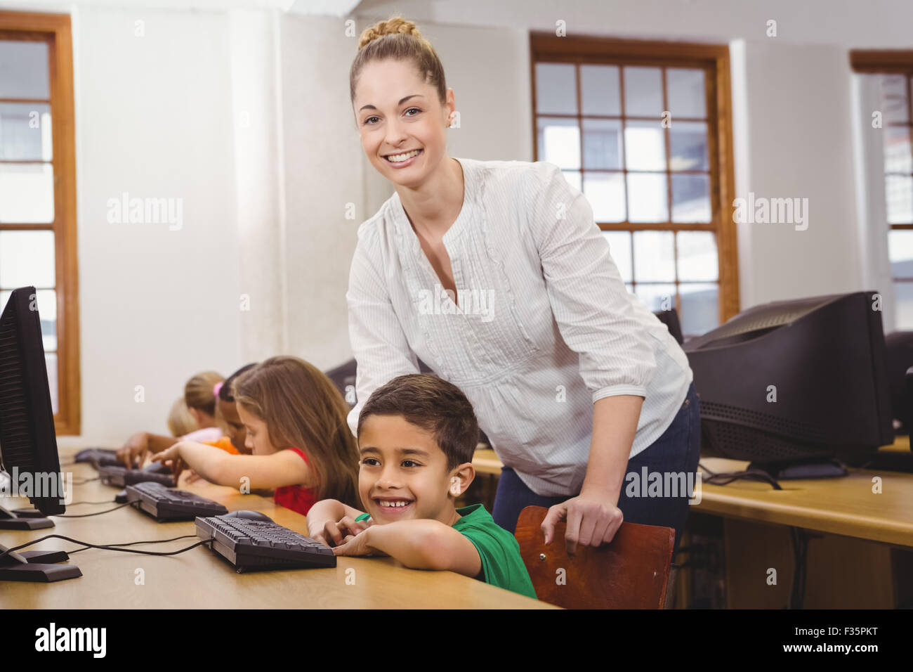 Teacher helping a student using a computer Stock Photo - Alamy