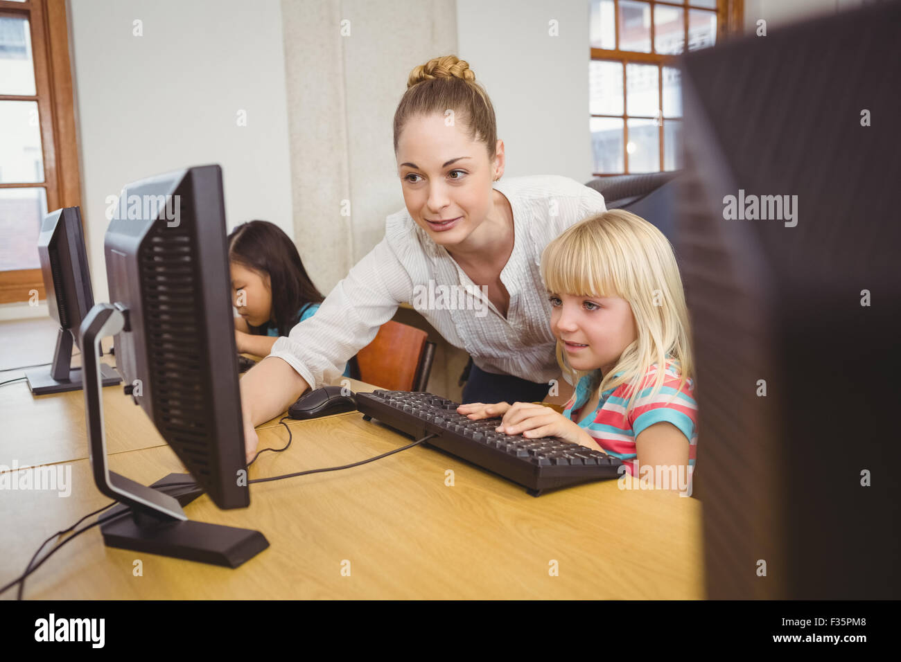 Teacher showing student how to use a computer Stock Photo - Alamy