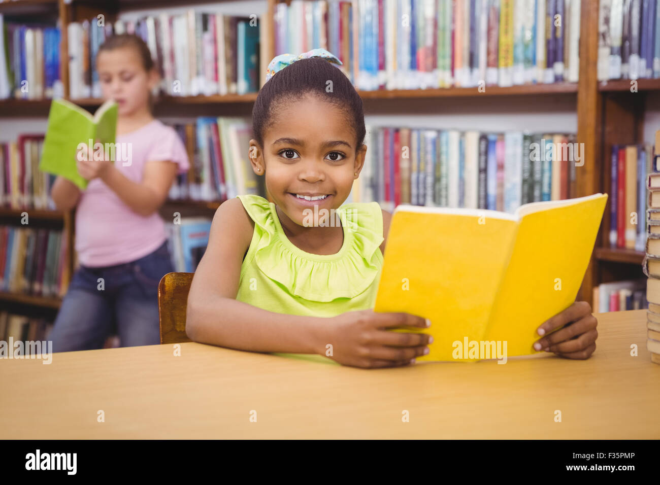 Happy pupil reading a library book Stock Photo - Alamy