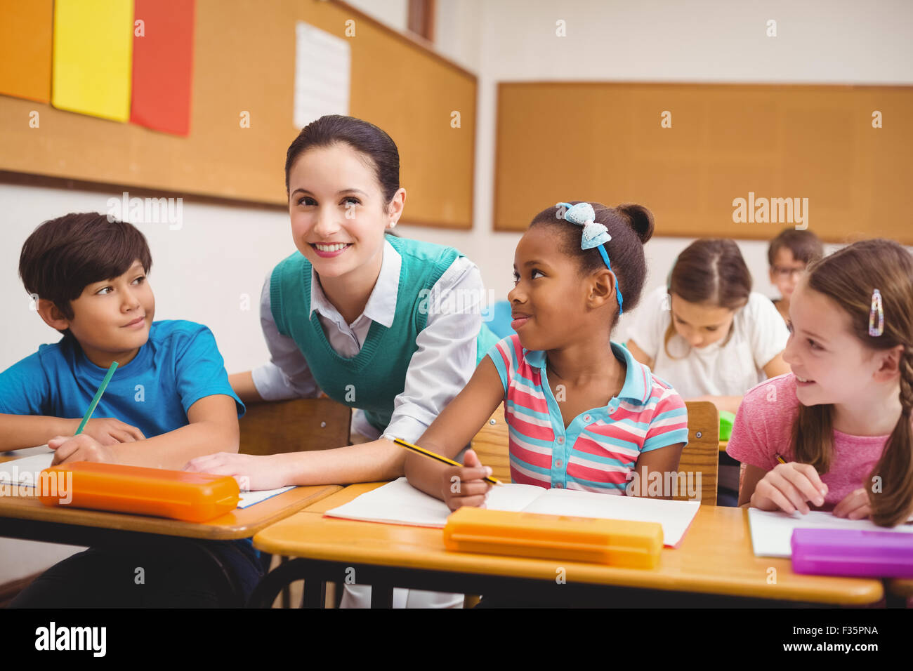 Teacher helping pupils during class Stock Photo - Alamy