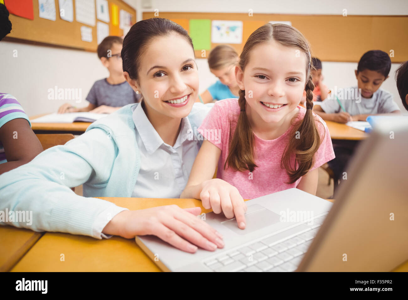 Teacher using laptop with pupil Stock Photo - Alamy
