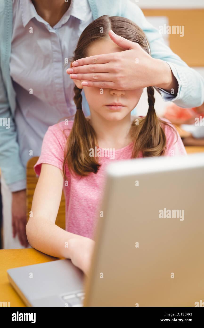 Teacher covering pupils eyes at laptop Stock Photo - Alamy