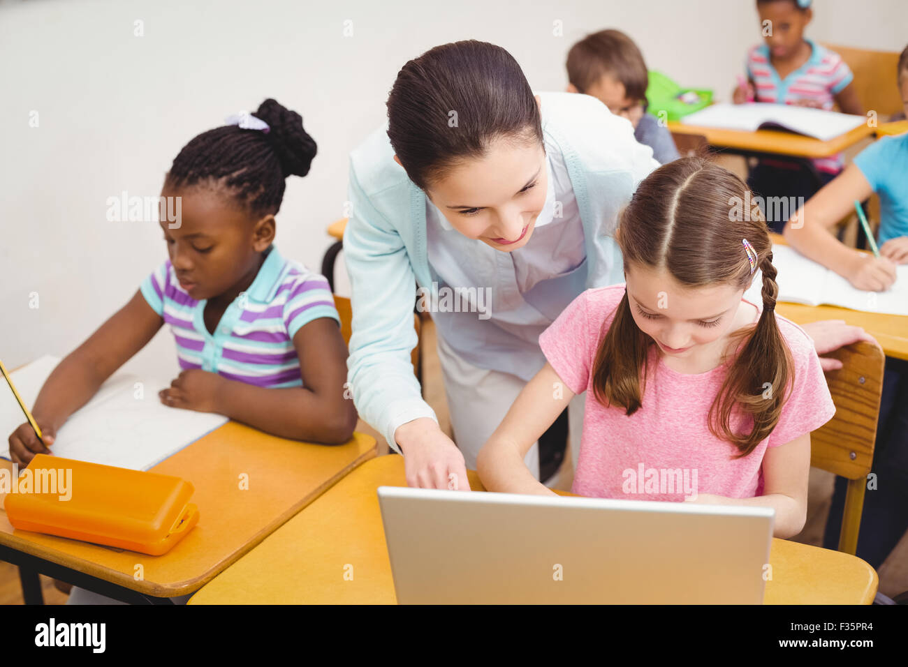 Teacher using laptop with pupil Stock Photo - Alamy
