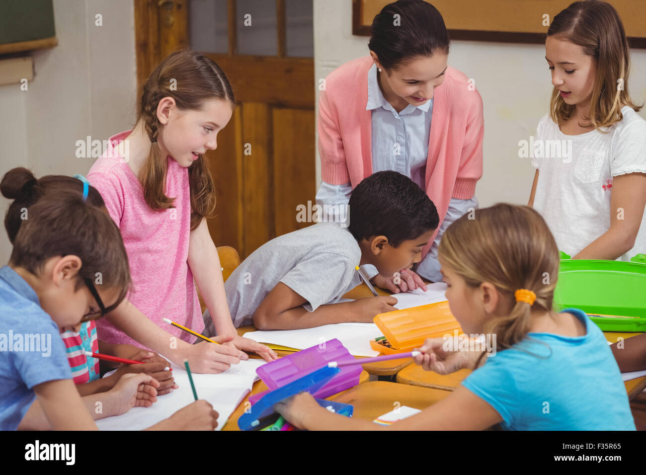 Teacher and pupils working at desk together Stock Photo - Alamy
