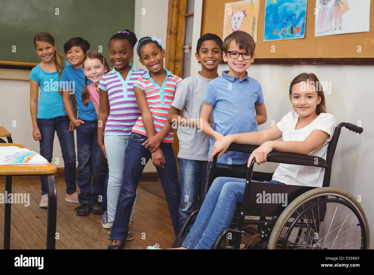 Disabled pupil smiling at camera with classmates Stock Photo - Alamy