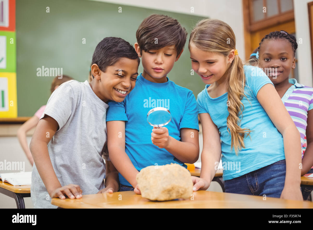 Pupils looking at rock with magnifying glass Stock Photo - Alamy