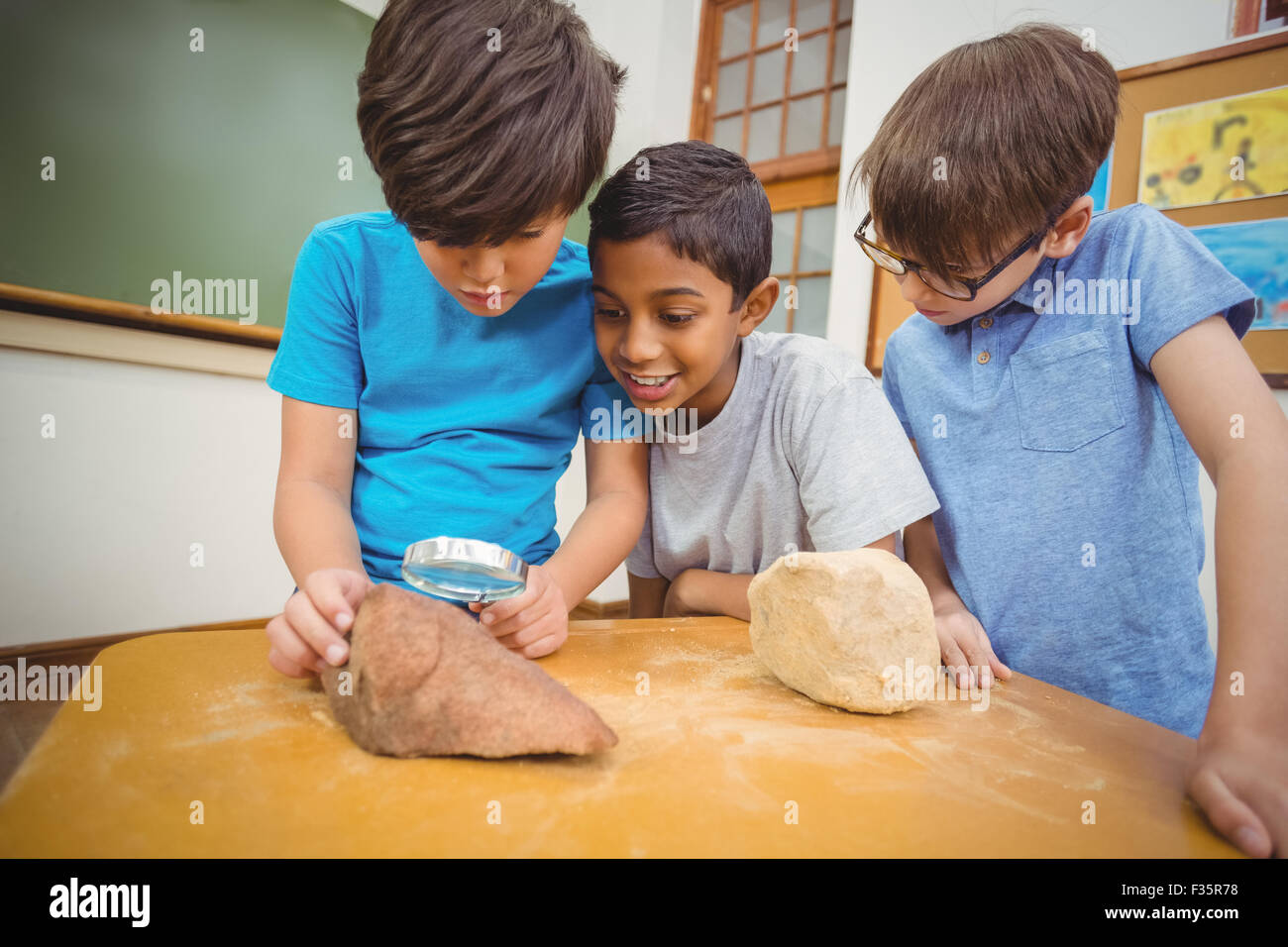 Pupils looking at rock with magnifying glass Stock Photo - Alamy