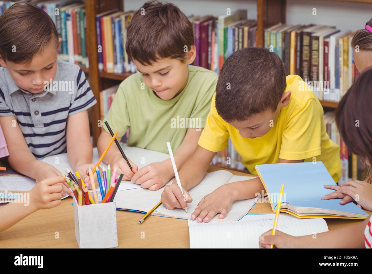 Pupils working together at desk in library Stock Photo - Alamy