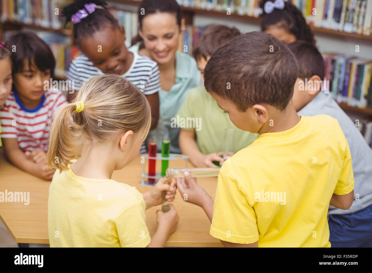 Pupils and teacher doing science in library Stock Photo - Alamy