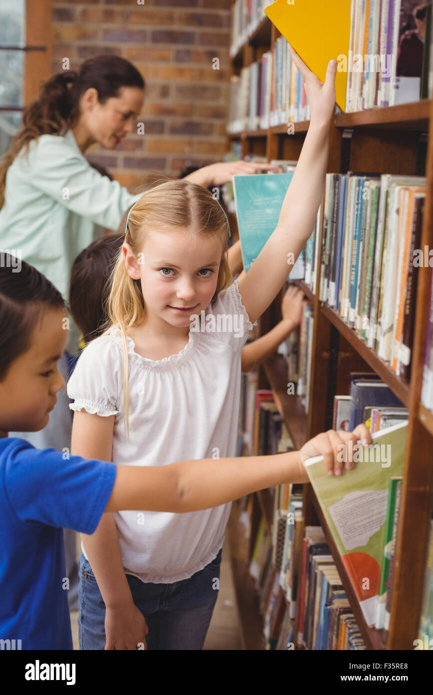 Pupils taking books from shelf in library Stock Photo - Alamy
