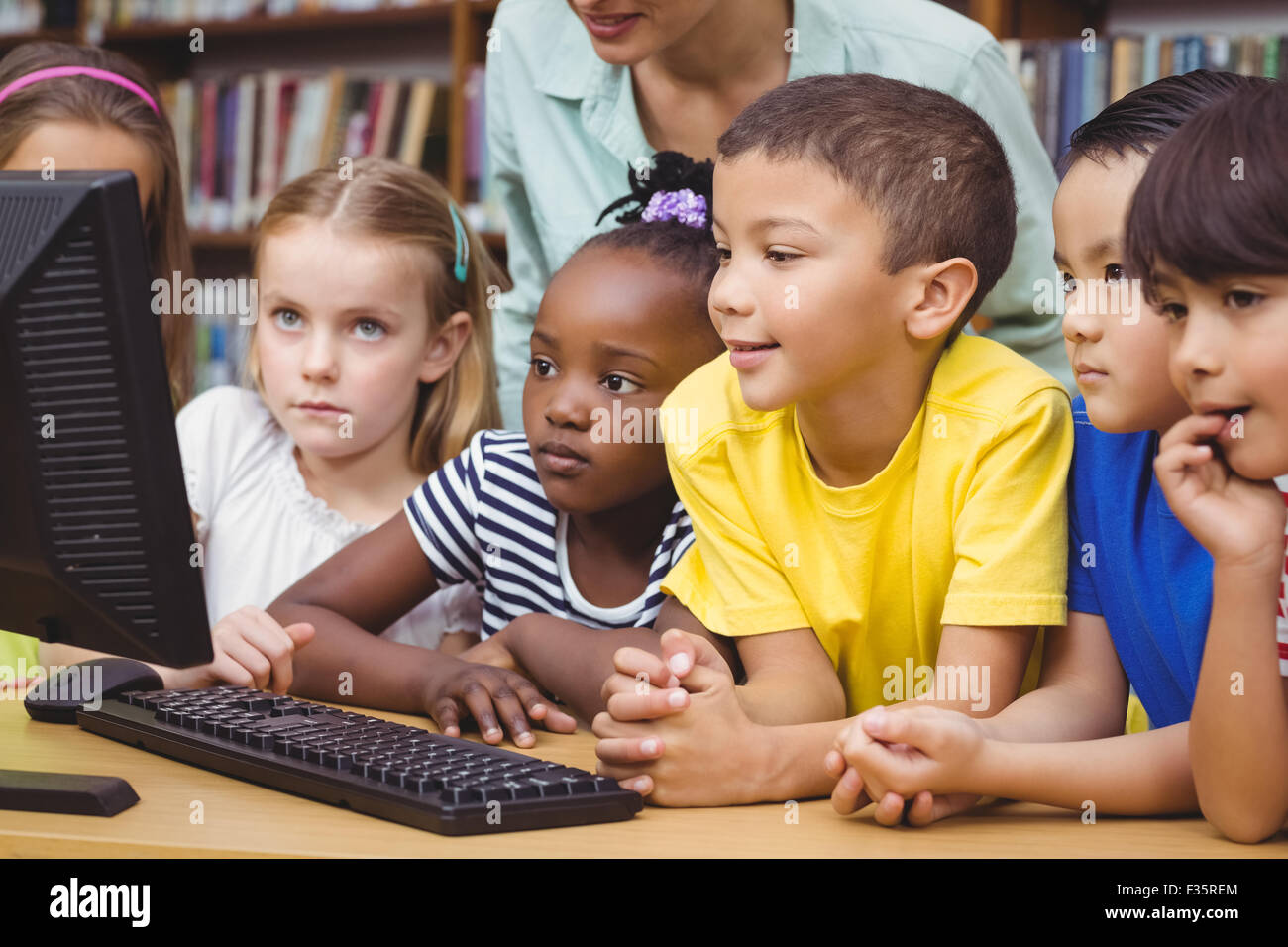 Pupils and teacher in the library using computer Stock Photo - Alamy