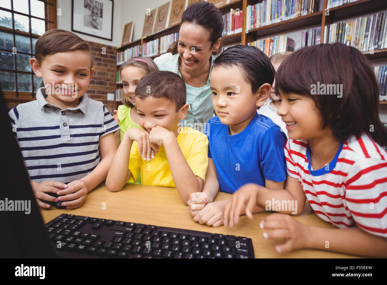 Pupils and teacher in the library using computer Stock Photo - Alamy