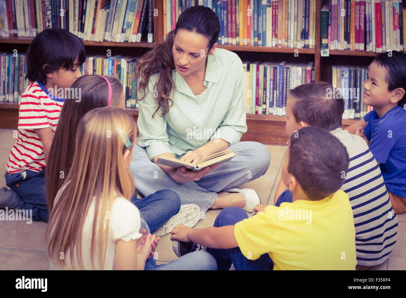 Teacher reading her pupils a story Stock Photo - Alamy
