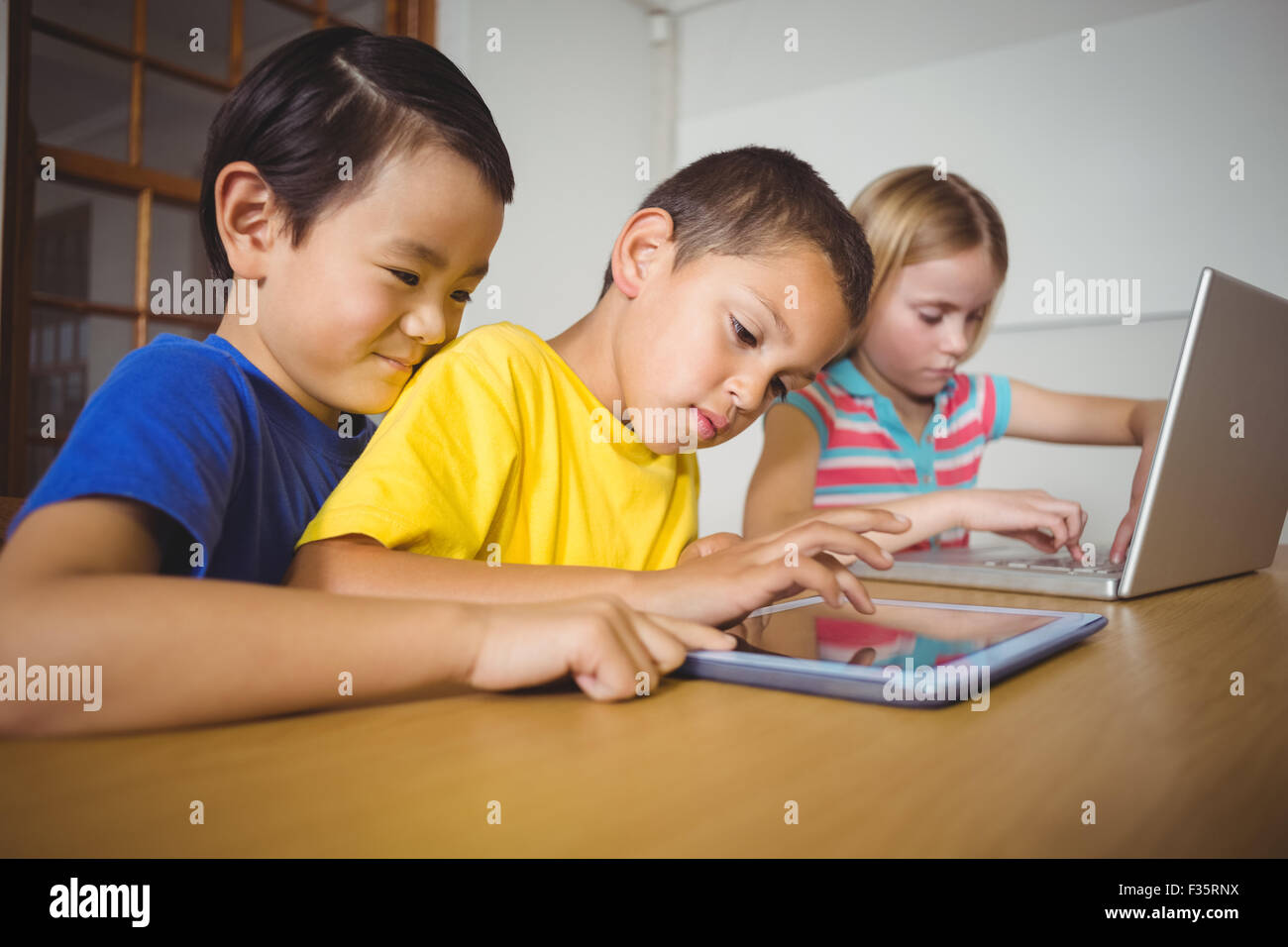 Cute pupils in class using laptop and tablet Stock Photo - Alamy