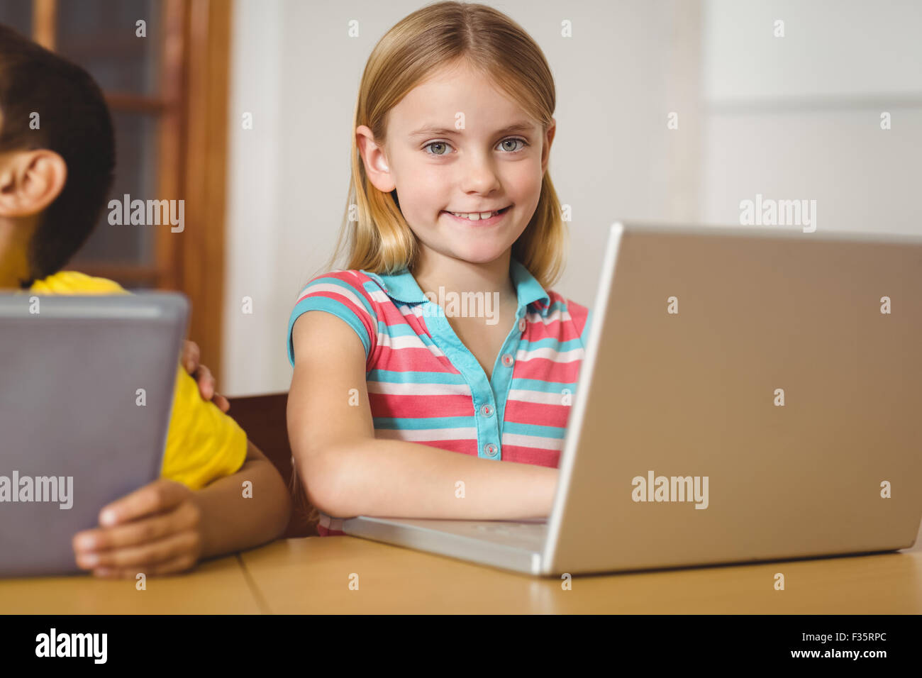 Cute pupil in class using laptop Stock Photo - Alamy