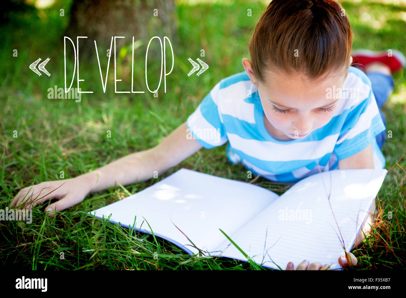 Develop against cute little girl reading in park Stock Photo - Alamy