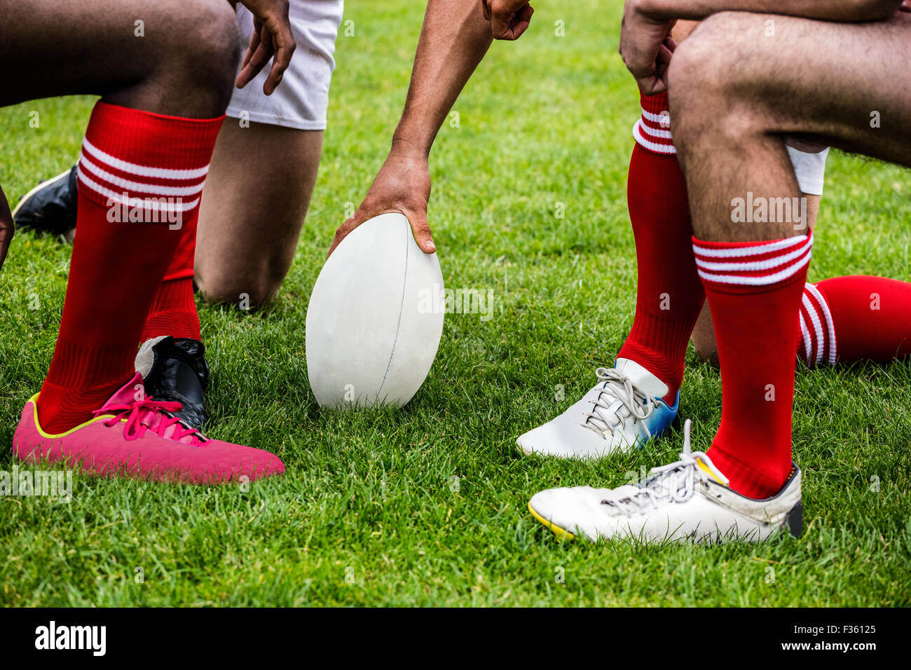 Rugby players in huddle with ball Stock Photo - Alamy