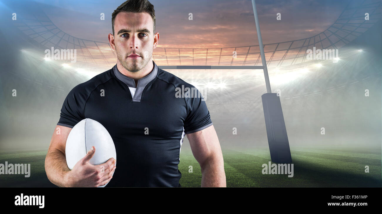 Composite image of tough rugby player holding ball Stock Photo - Alamy