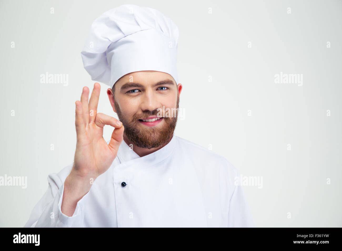 Portrait of a smiling male chef cook showing ok sign isolated on a ...