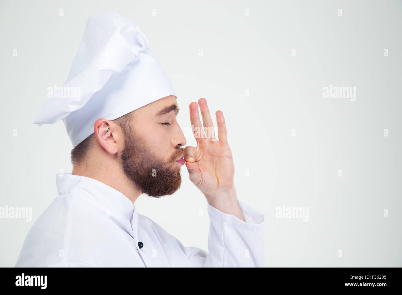 Portrait of a male chef cook smelling something in fingers isolated on ...