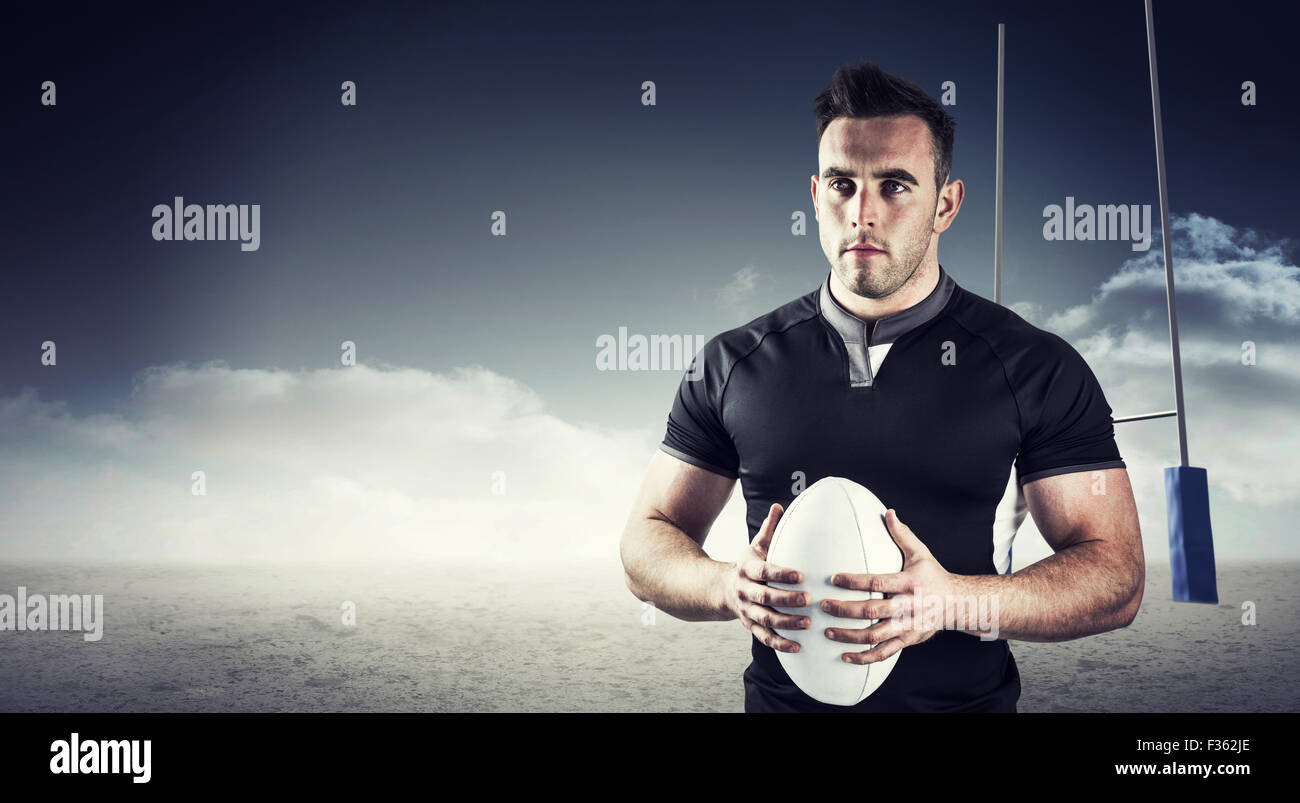 Composite image of tough rugby player holding ball Stock Photo - Alamy