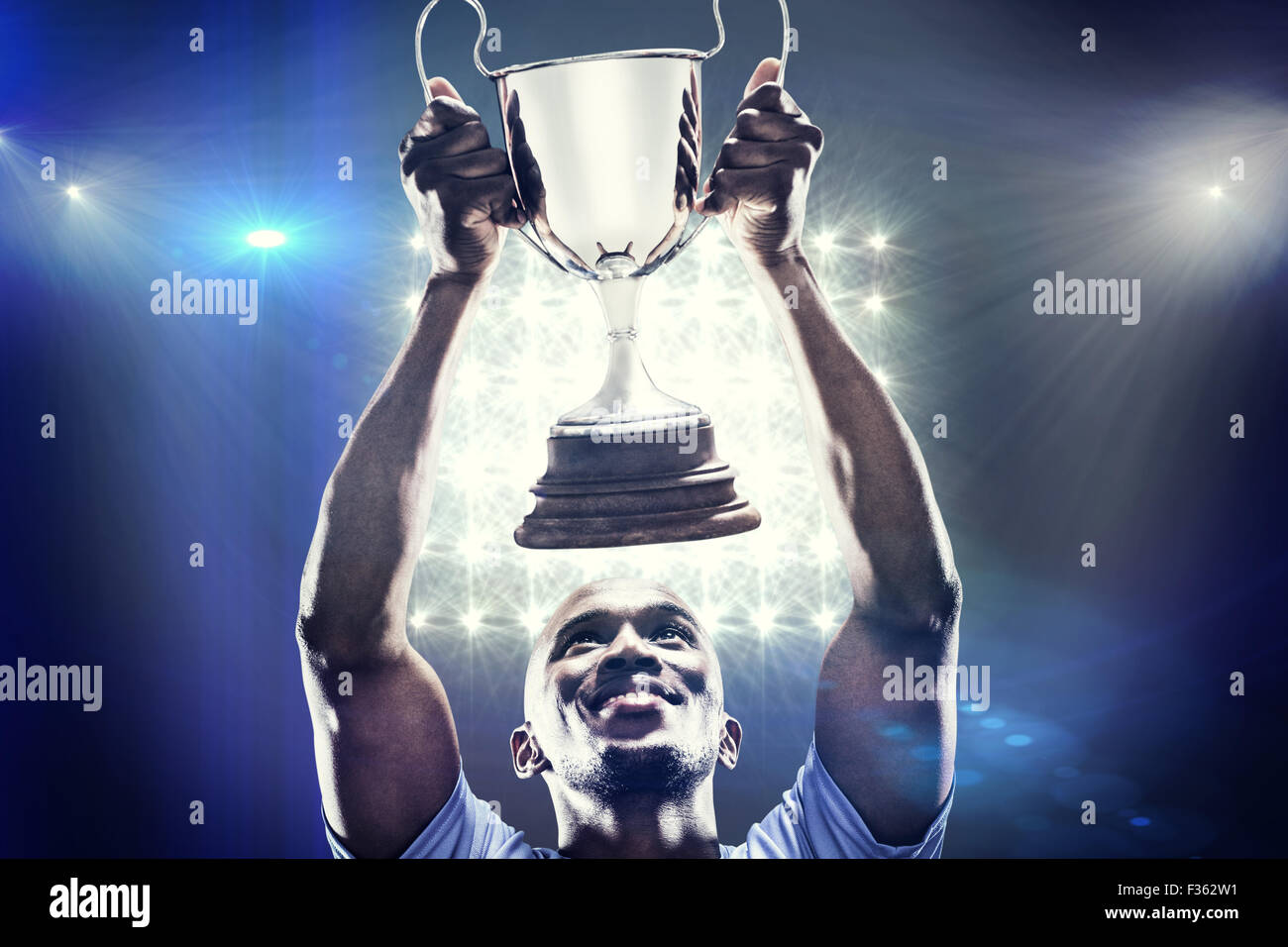 Composite image of happy sportsman looking up while holding trophy ...