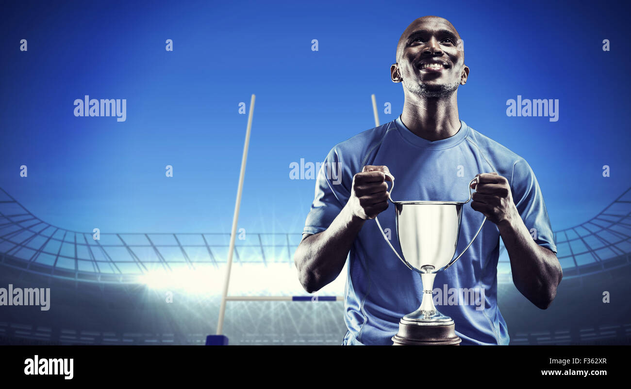 Composite image of happy athlete holding trophy looking up Stock Photo ...