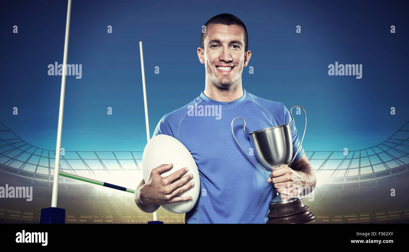Composite image of portrait of smiling rugby player holding trophy and ...