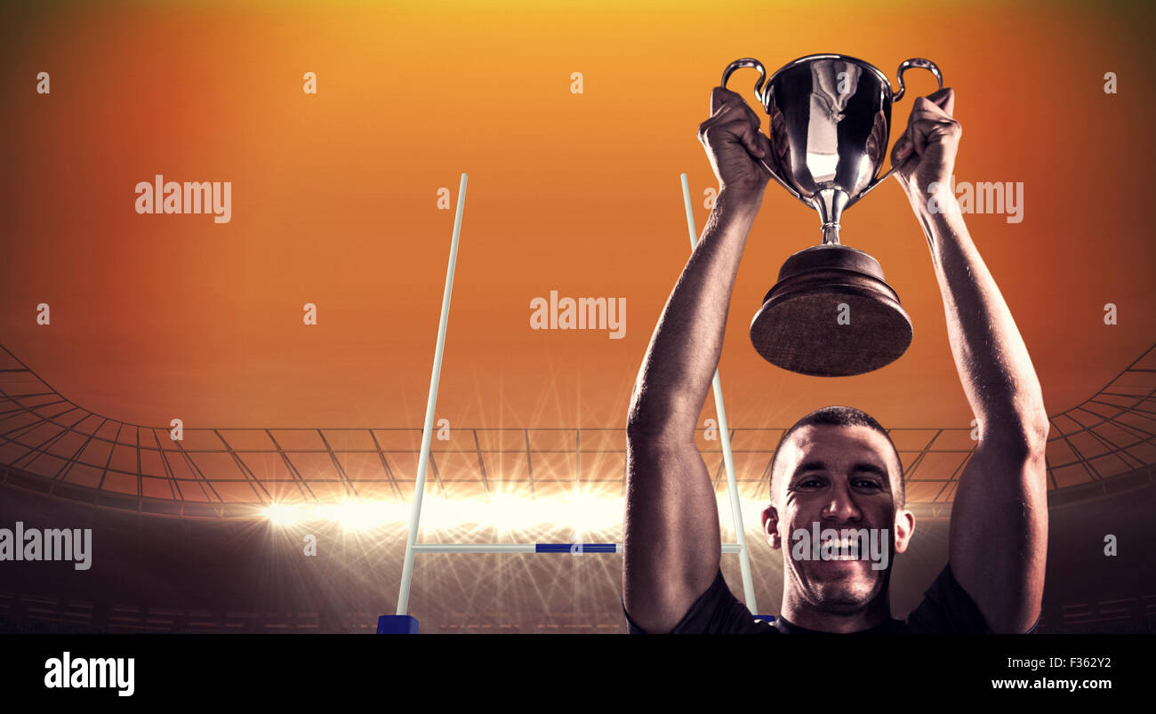 Composite image of portrait of successful rugby player holding trophy ...