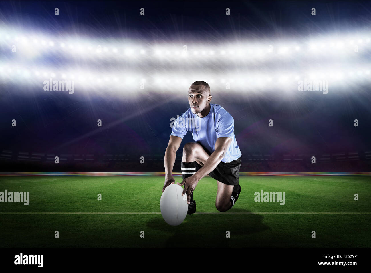 Composite image of rugby player holding ball while kneeling Stock Photo ...