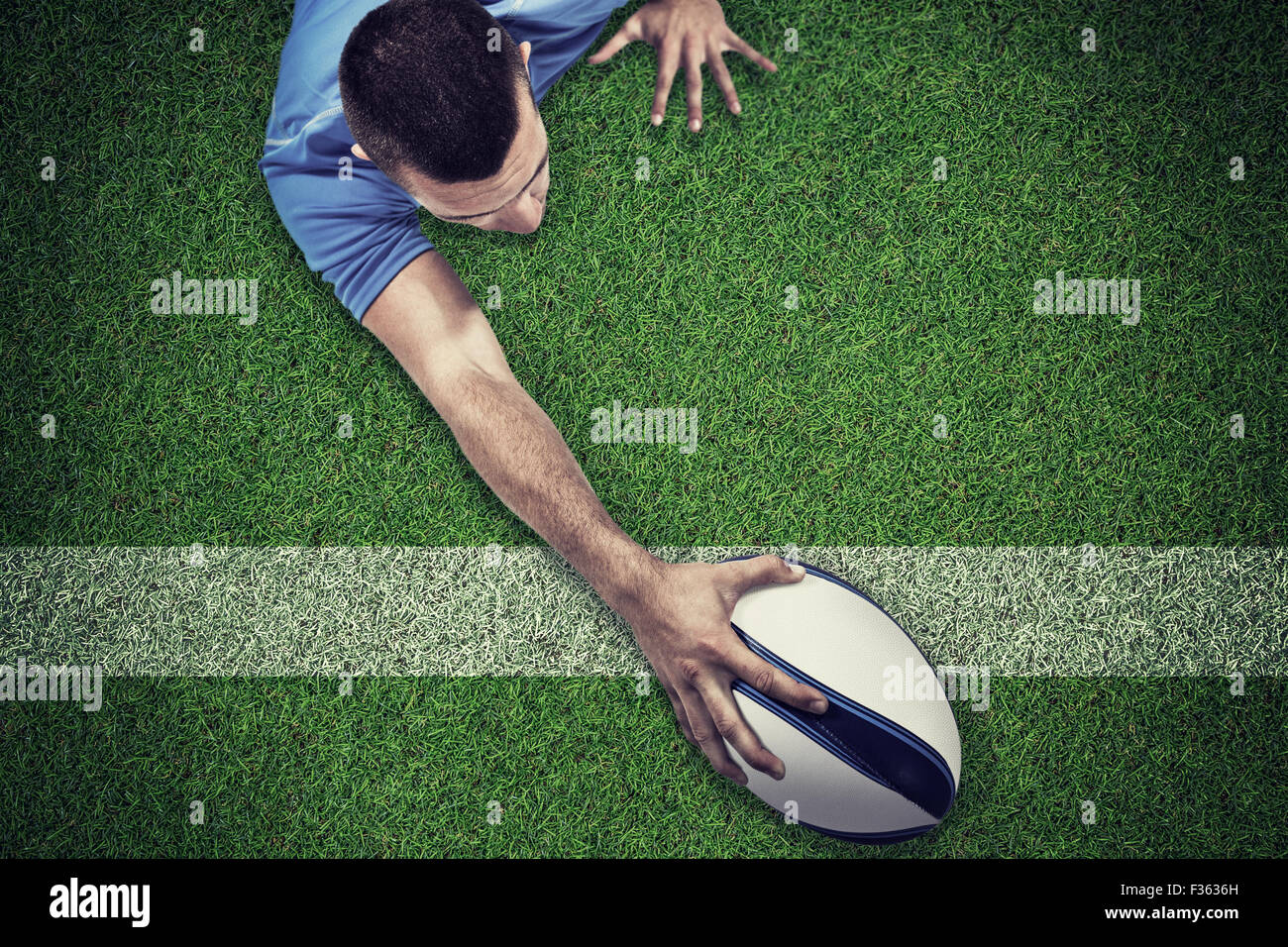 Composite image of rear view of rugby player lying in front with ball ...