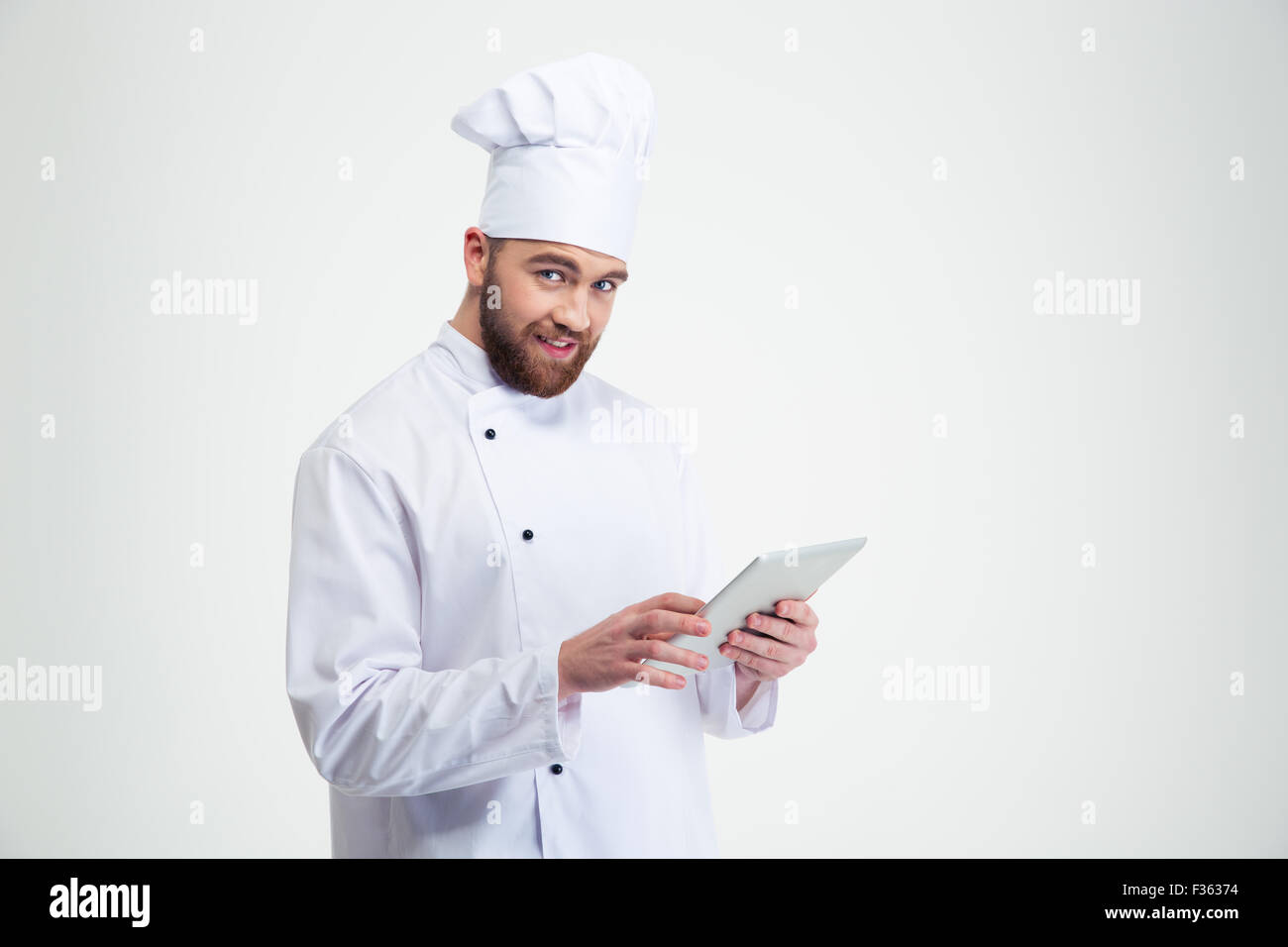 Portrait of a smiling chef cook holding tablet computer isolated on a ...