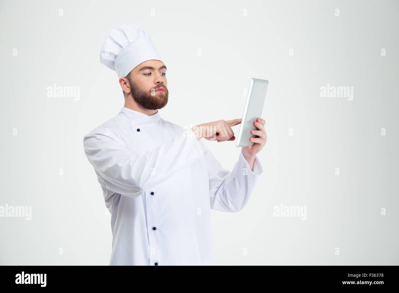 Portrait of a male chef cook using tablet computer isolated on a white ...