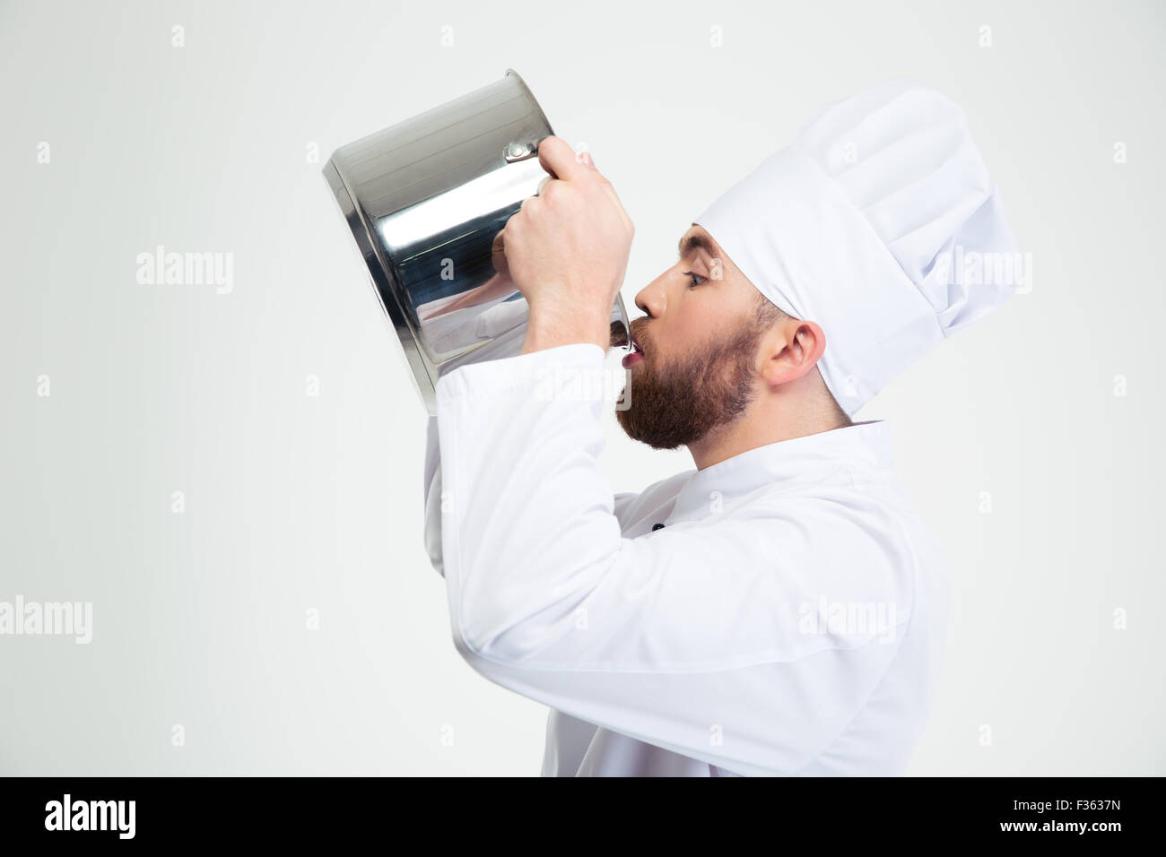 Portrait of a male chef cook drinking from pot isolated on a white ...