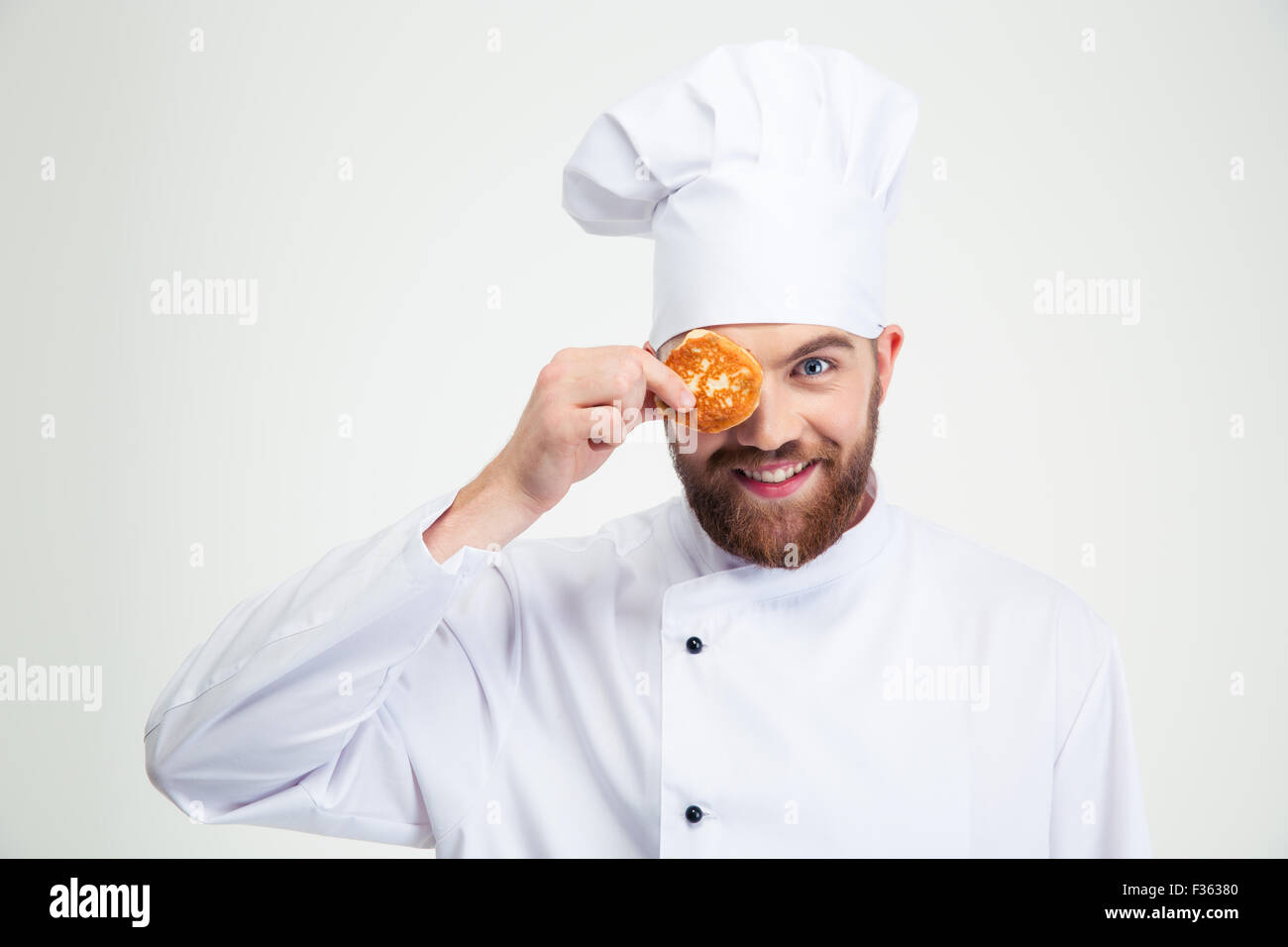 Portrait of a smiling male chef cook covering his eye with pancake ...