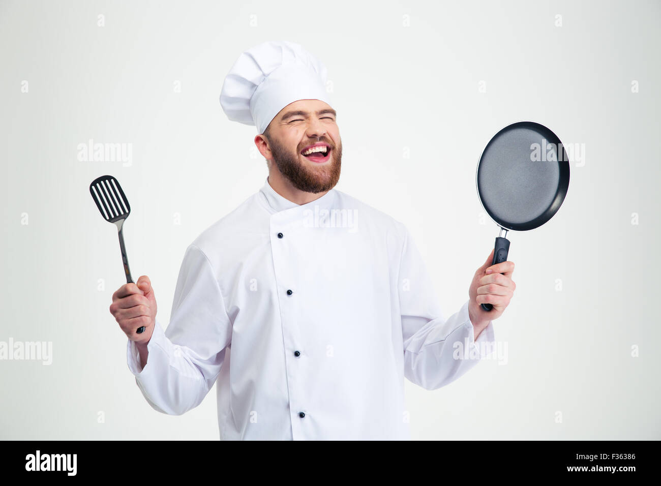 Portrait of a laughing male chef cook holding spoon and pan isolated on ...
