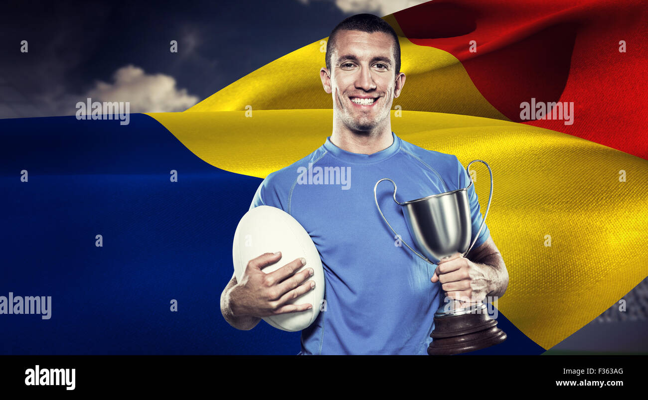 Composite image of portrait of smiling rugby player holding trophy and ...