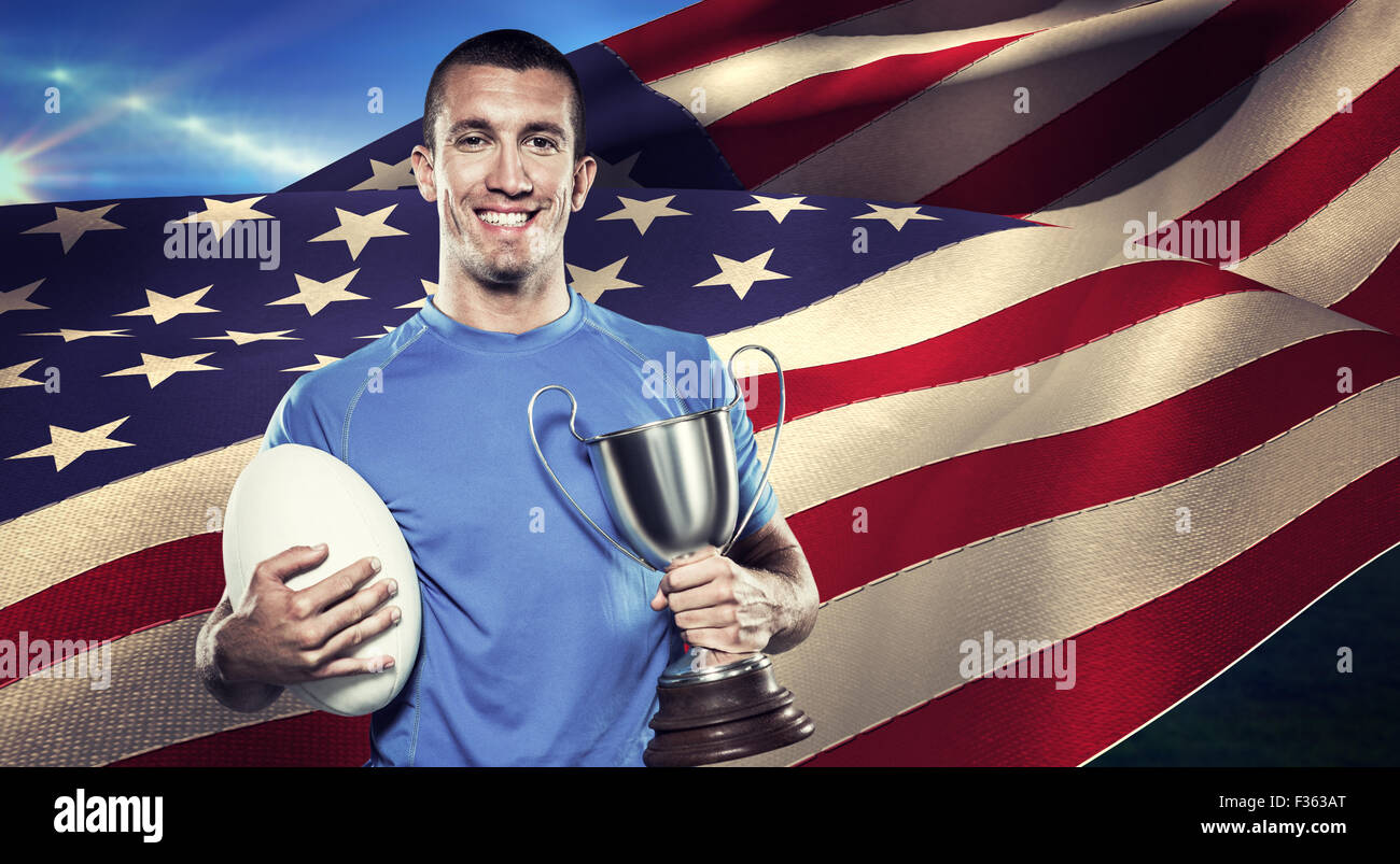 Composite image of portrait of smiling rugby player holding trophy and ...