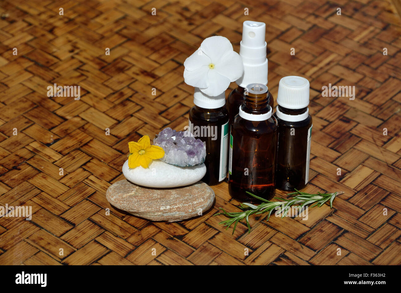 Bottles of homeopathic remedies, plants and stones on wooden table ...