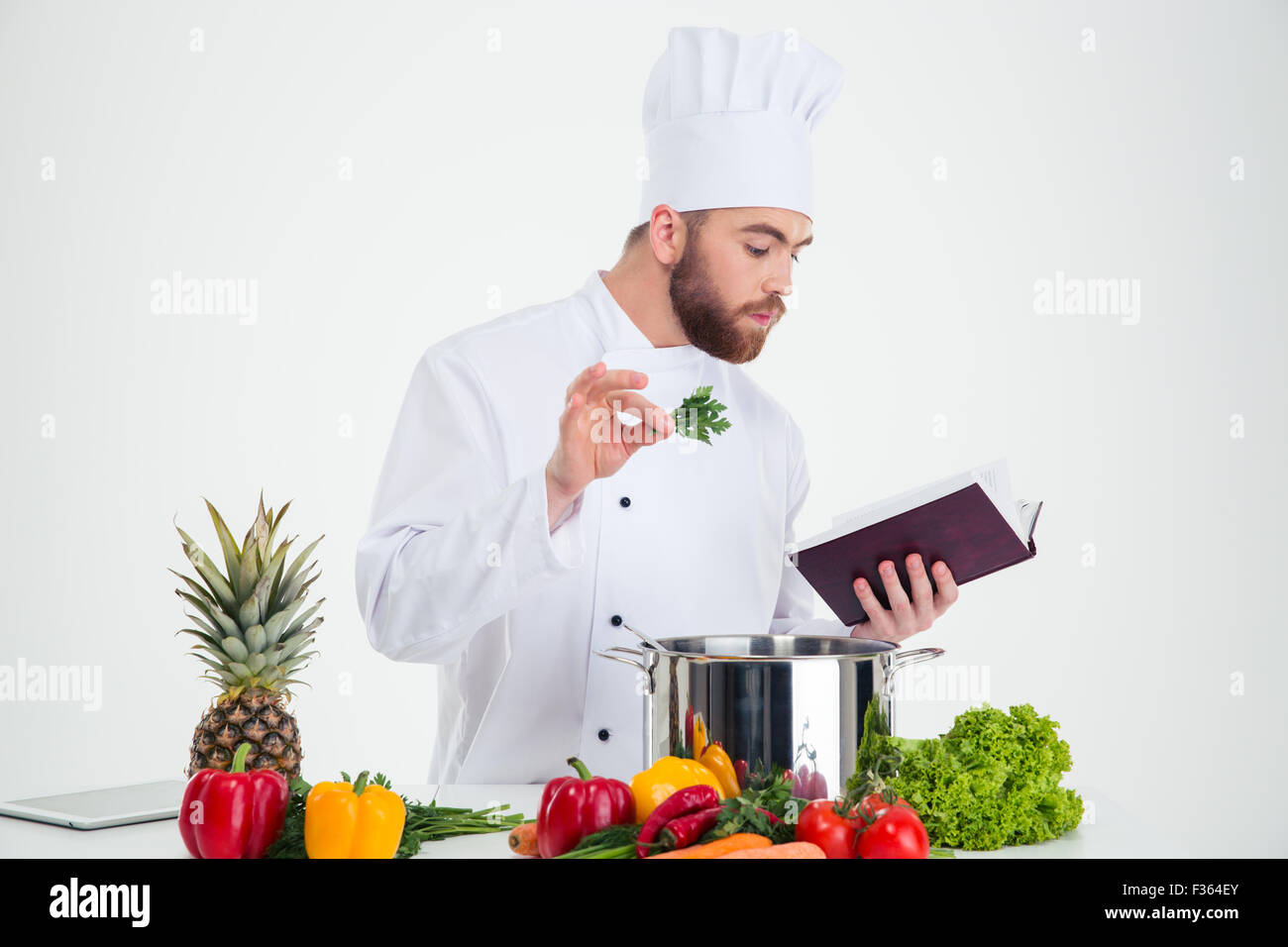 Portrait of a handsome male chef cook reading recipe book while ...