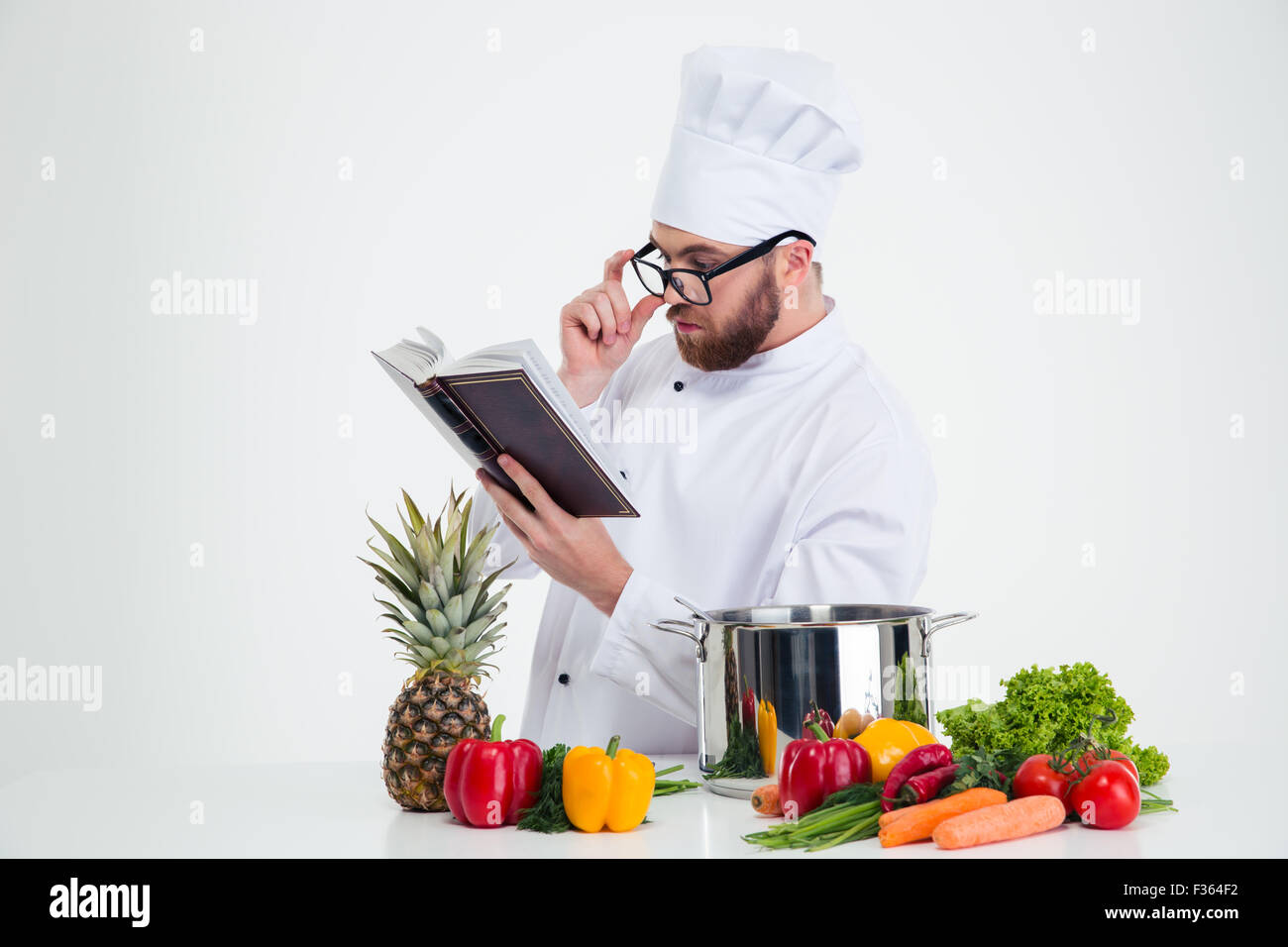 Portrait of a male chef cook in glasses reading recipe book isolated on ...