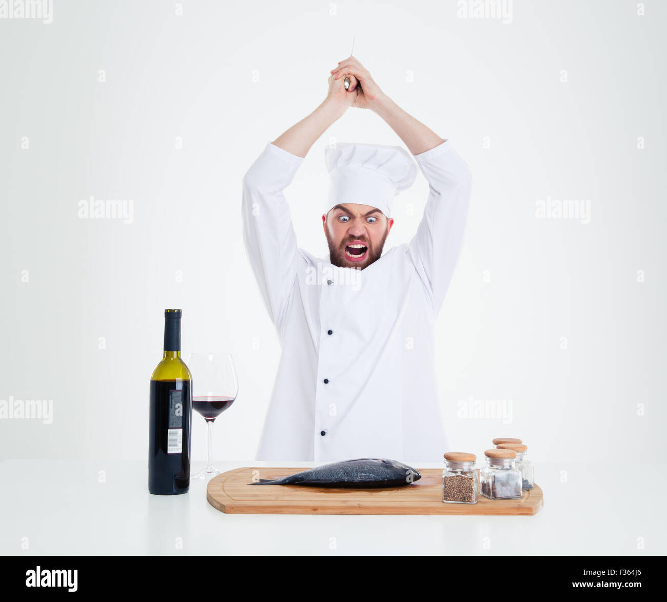 Portrait of angry male chef cook cutting fish isolated on a white ...