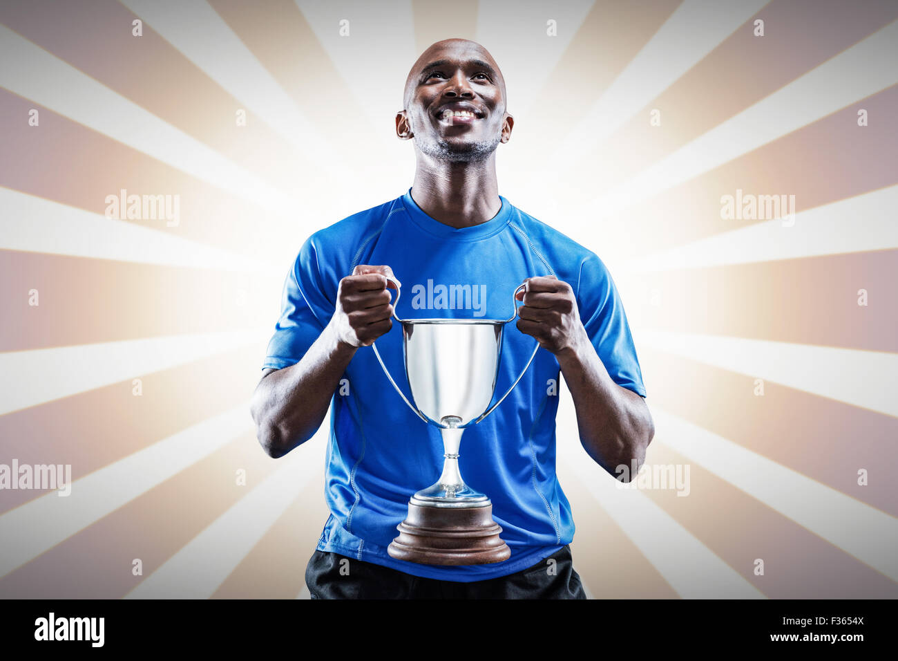 Composite image of happy athlete holding trophy looking up Stock Photo ...