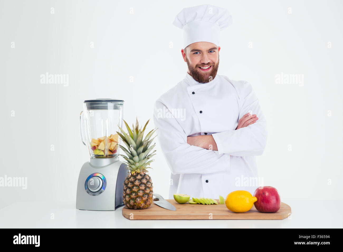 Portrait of a smiling chef cook standing with arms folded near table ...