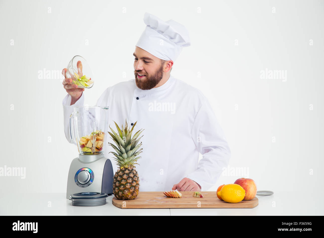 Portrait of a happy male chef cook using blender with fruits isolated ...