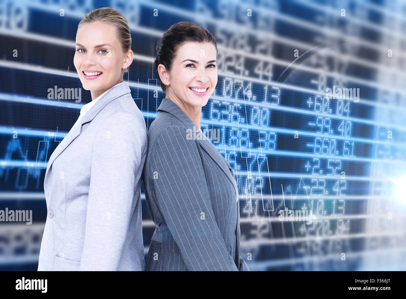 Serious young businesswomen standing back to back at office railing ...