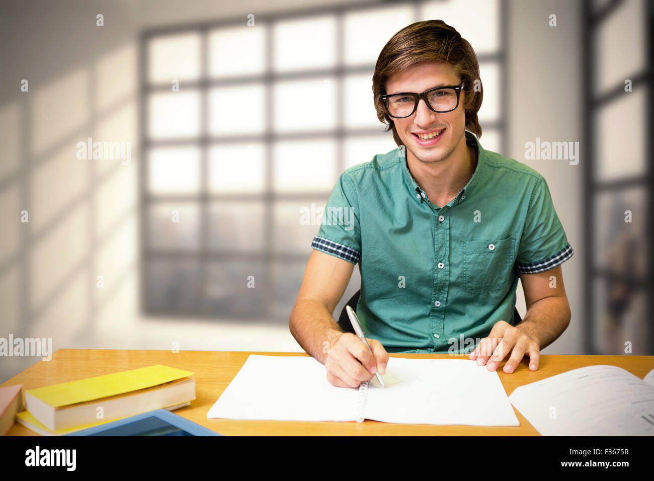Composite image of student sitting in library writing Stock Photo - Alamy