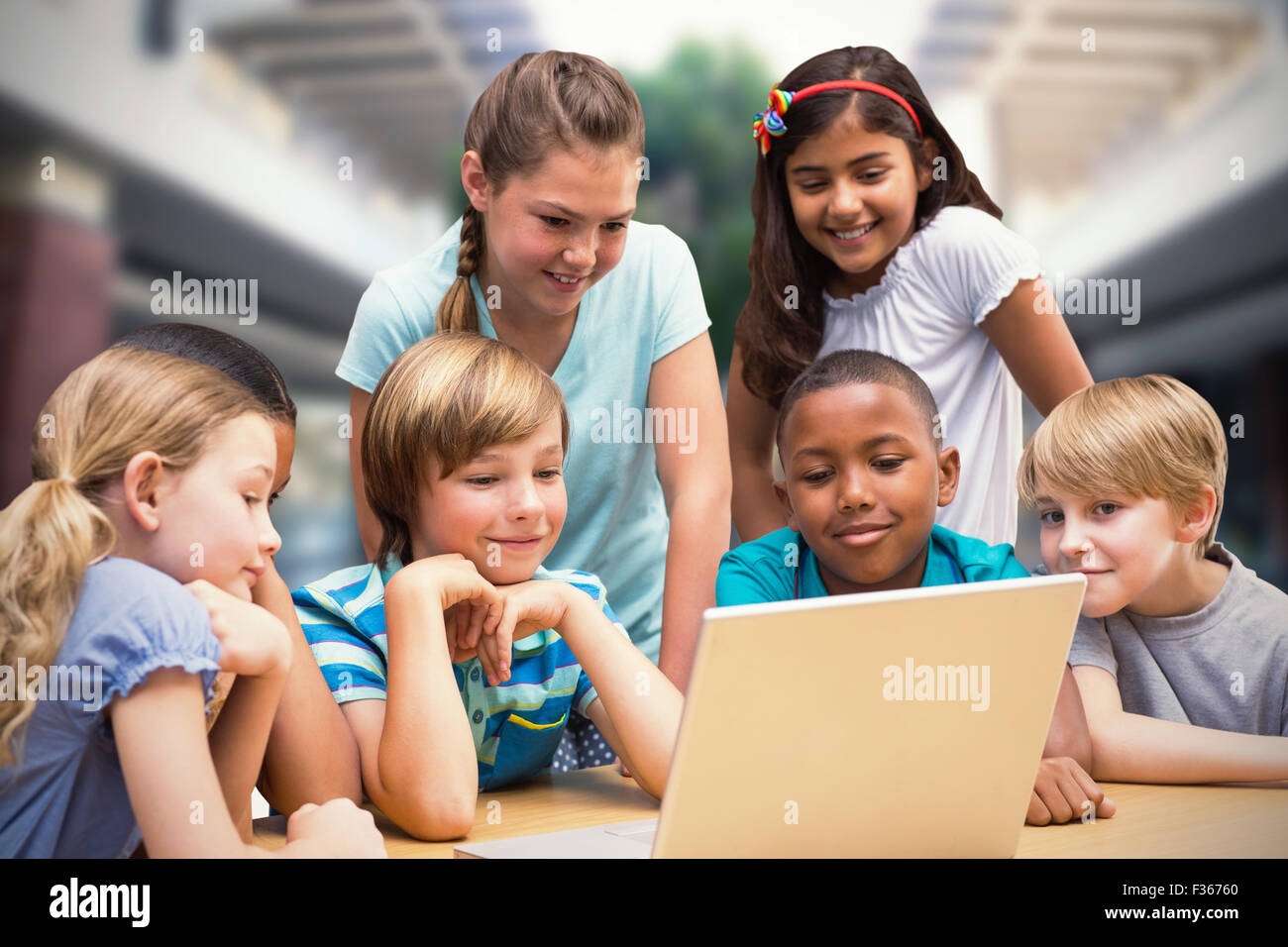 Composite image of cute pupils using tablet computer in library Stock ...