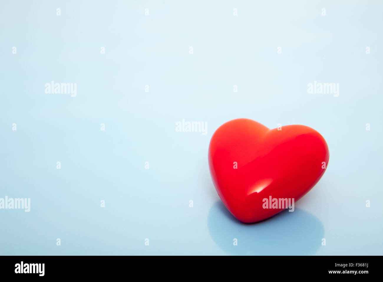 Single red heart on blue background Stock Photo - Alamy